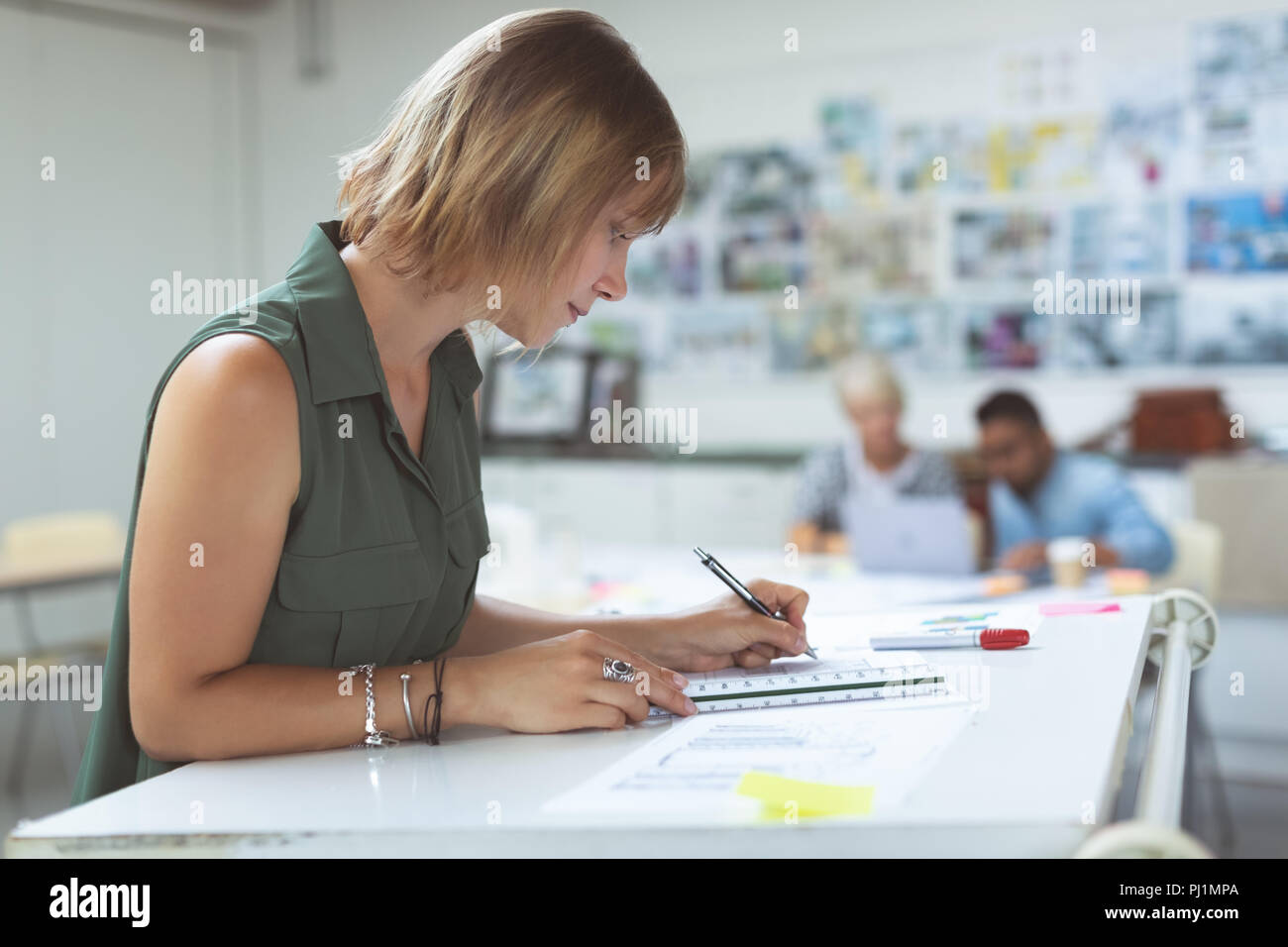 Female executive working on drafting table in office Stock Photo - Alamy