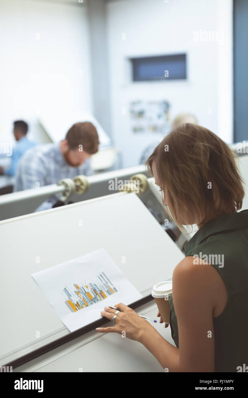 Female executive looking at blueprint on drafting table Stock Photo - Alamy