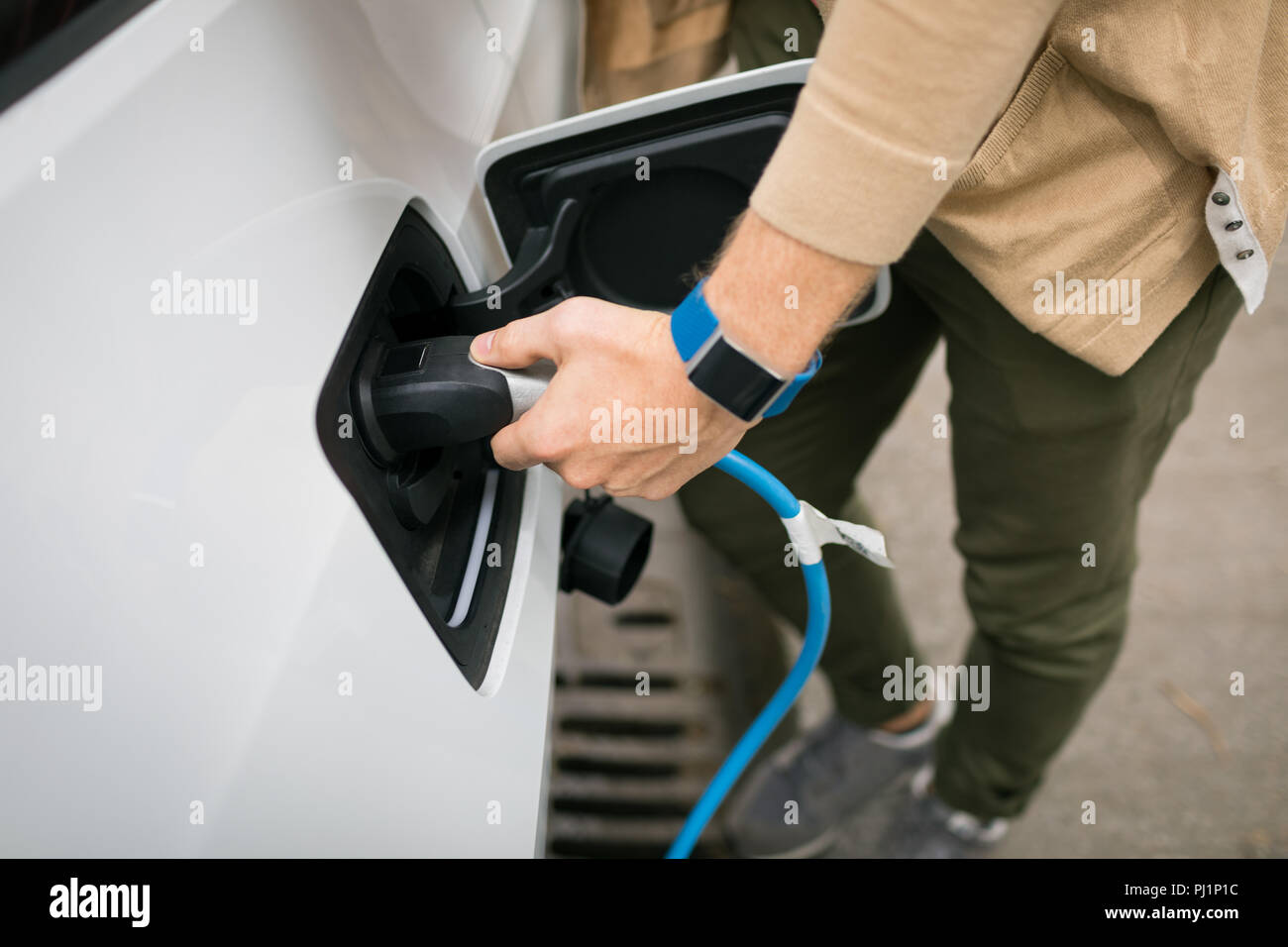 Man charging electric car at charging station Stock Photo - Alamy