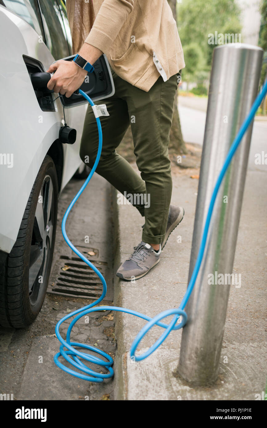 Man charging electric car at charging station Stock Photo - Alamy