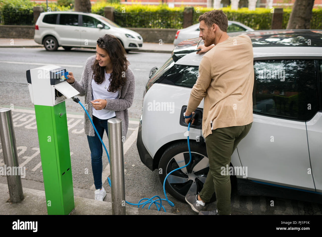 Couple charging electric car Stock Photo - Alamy