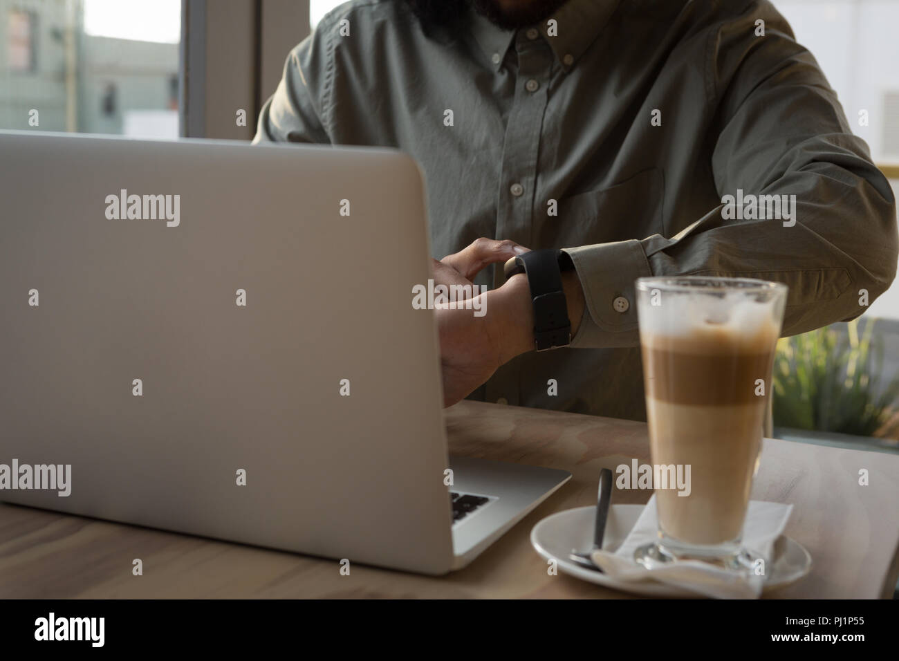 Man using smartwatch in cafe Stock Photo - Alamy