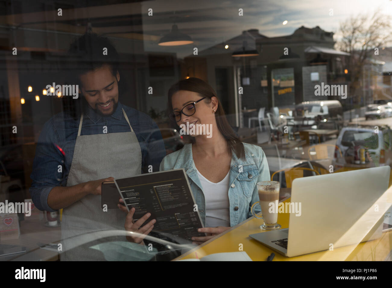 Woman discussing menu card with waiter Stock Photo - Alamy