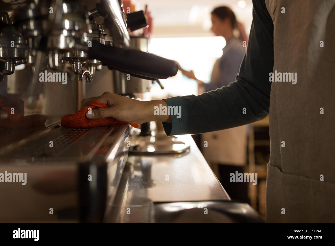 Waiter cleaning coffee machine at coffee counter Stock Photo - Alamy