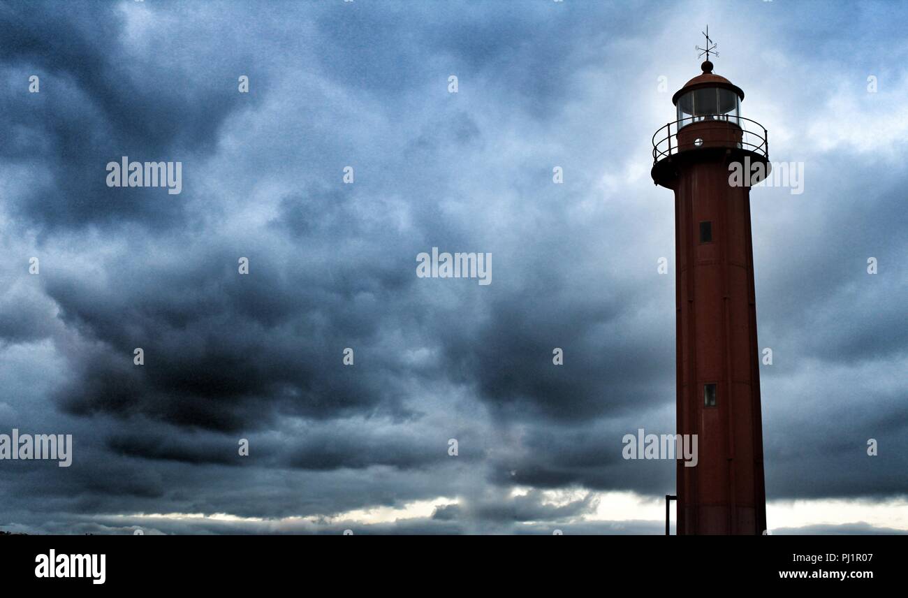 Red lighthouse in the port of Cacilhas village in Lisbon on a gray and ...