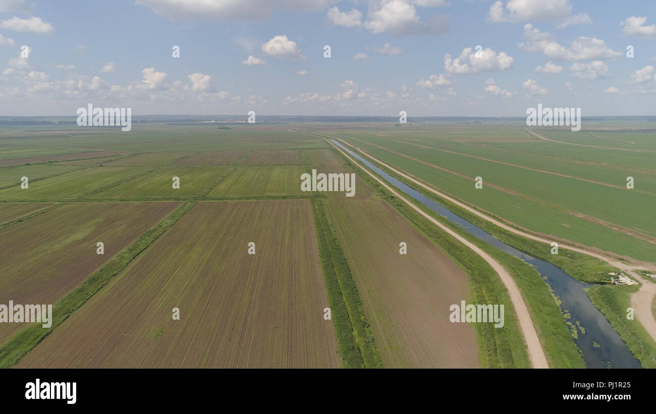 Aerial view of agricultural cultivated fields with irrigational channel ...
