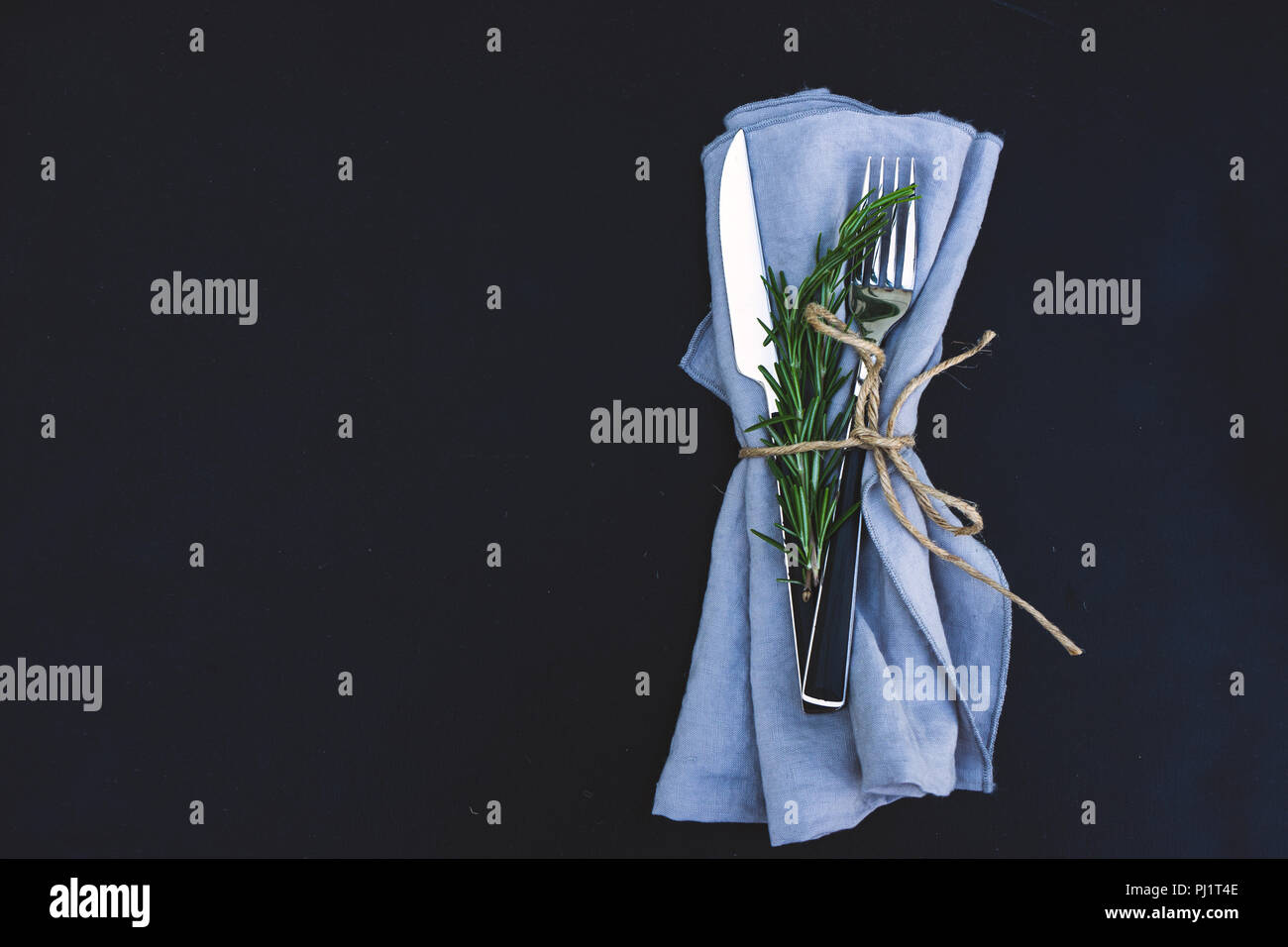 Rustic table setting with rosemary herb on dark wooden background with ...