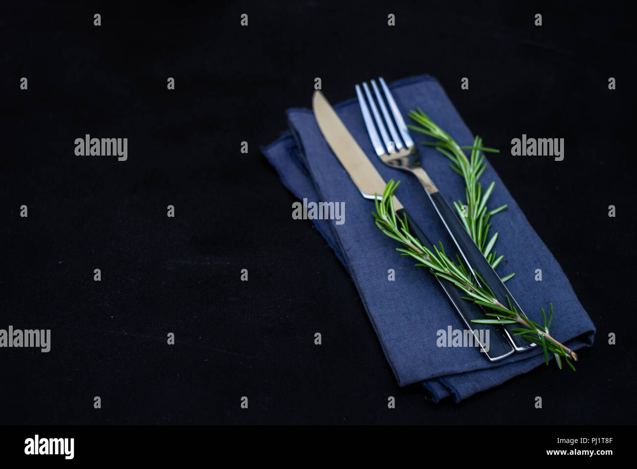 Rustic table setting with rosemary herb on dark wooden background with ...