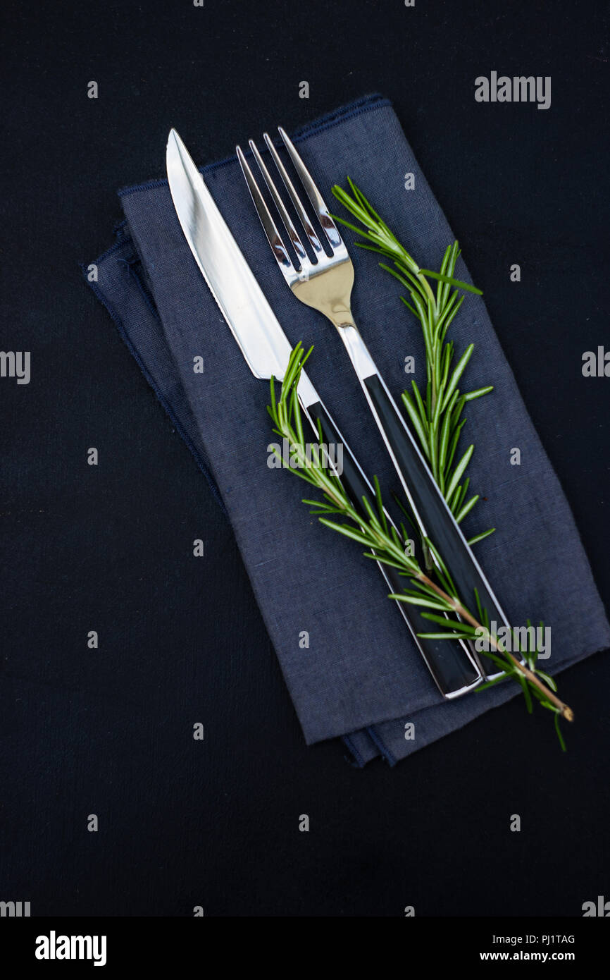 Rustic table setting with rosemary herb on dark wooden background with ...