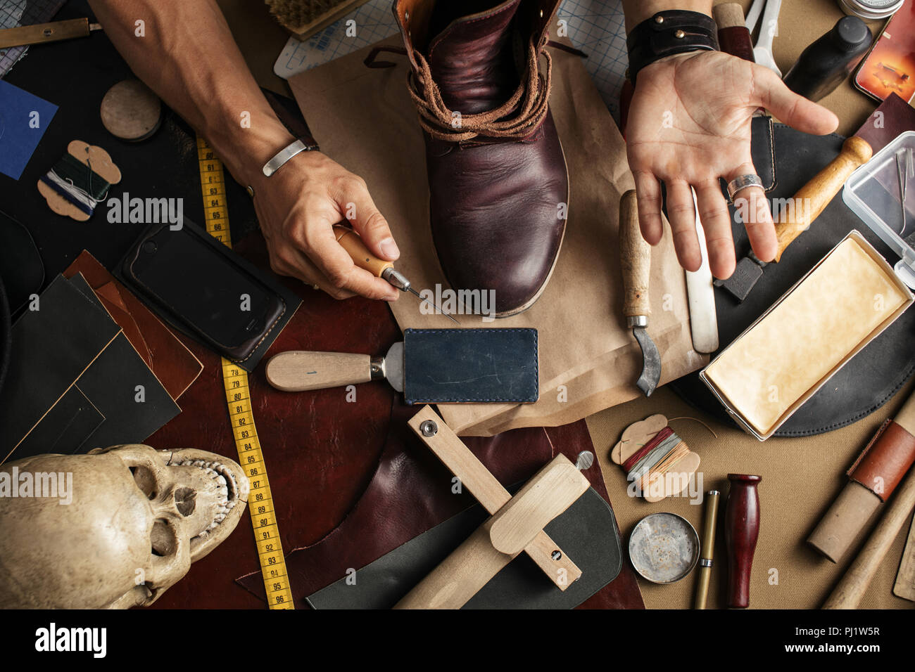 Close up of shoe maker hands producing boots in his leather workshop ...