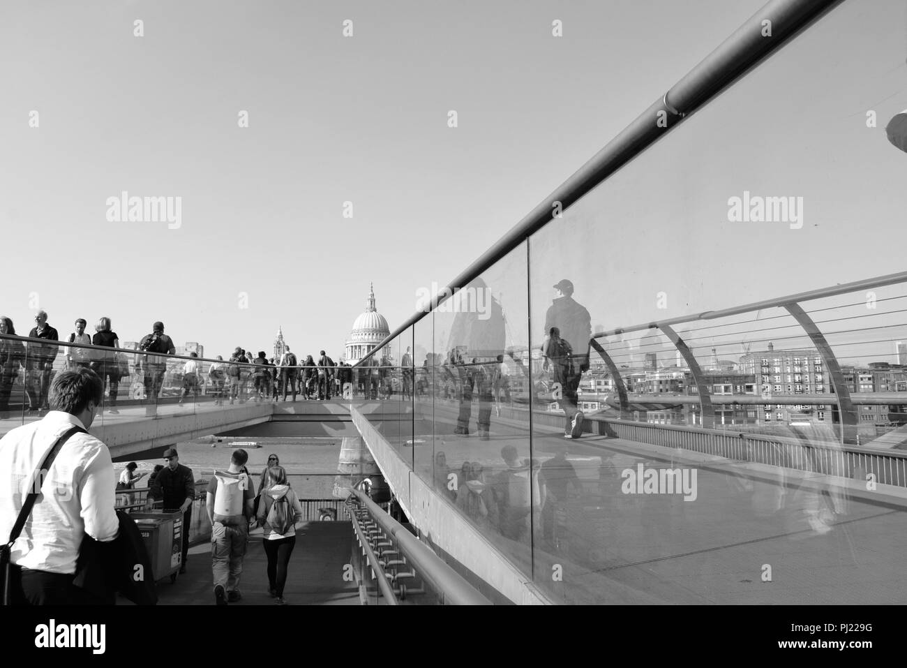 A Black and White landscape shot of people walking over the Millenium ...