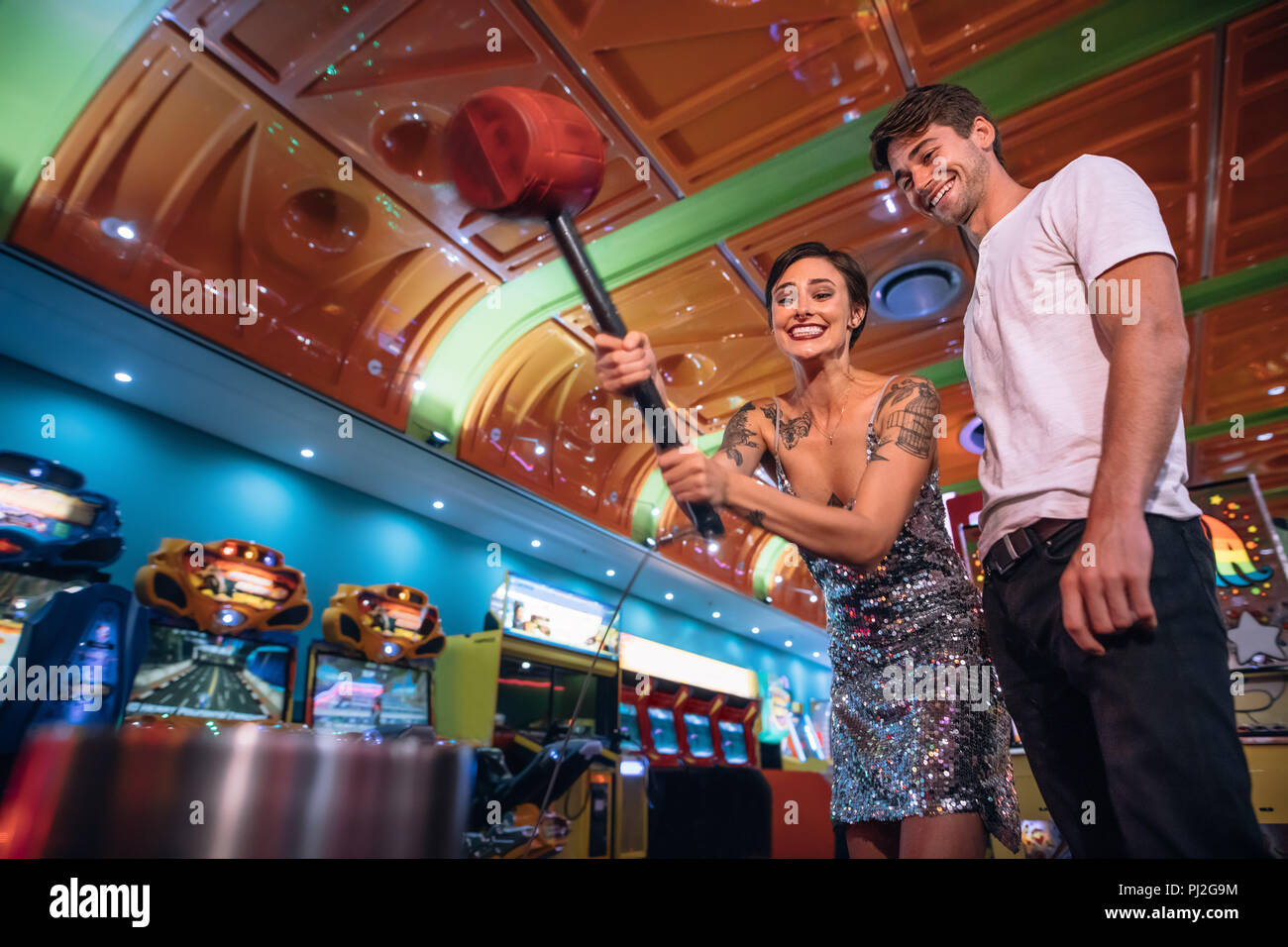Happy couple at a gaming arcade having fun playing games. Woman playing ...