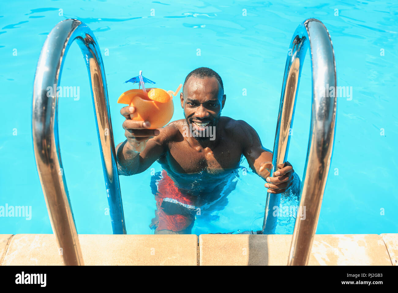 The portrait of happy smiling beautiful man at the swimming pool ...
