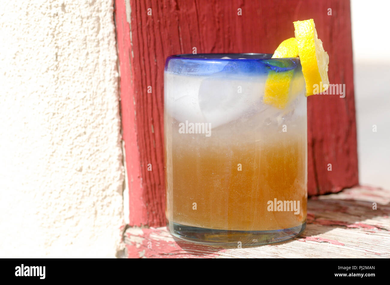 Half lemonade, half ice tea with a slice of lemon and a red background ...
