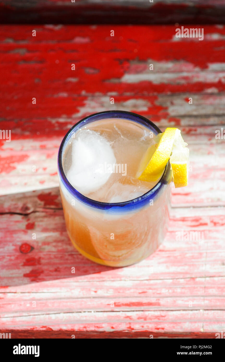 Half lemonade, half ice tea with a slice of lemon and a red background ...