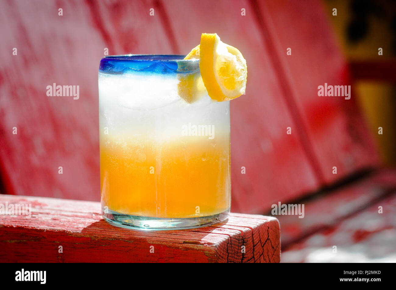 Half lemonade, half ice tea with a slice of lemon and a red background ...