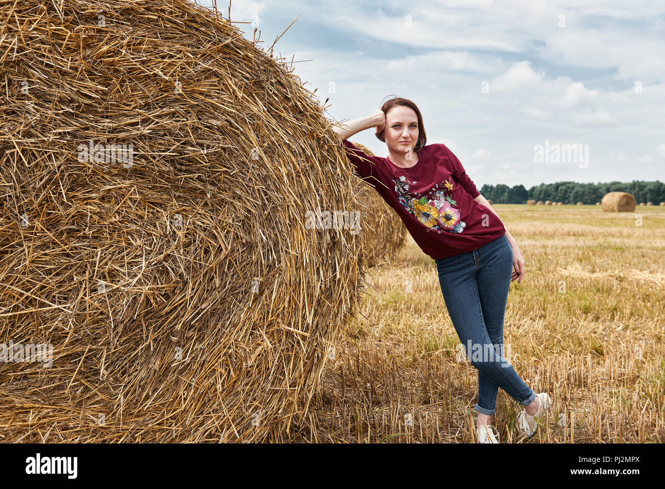 young girl having fun in the field, pushes the haystack Stock Photo - Alamy