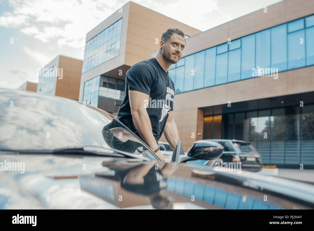Close up of young attractive man getting out of the black car. Side ...