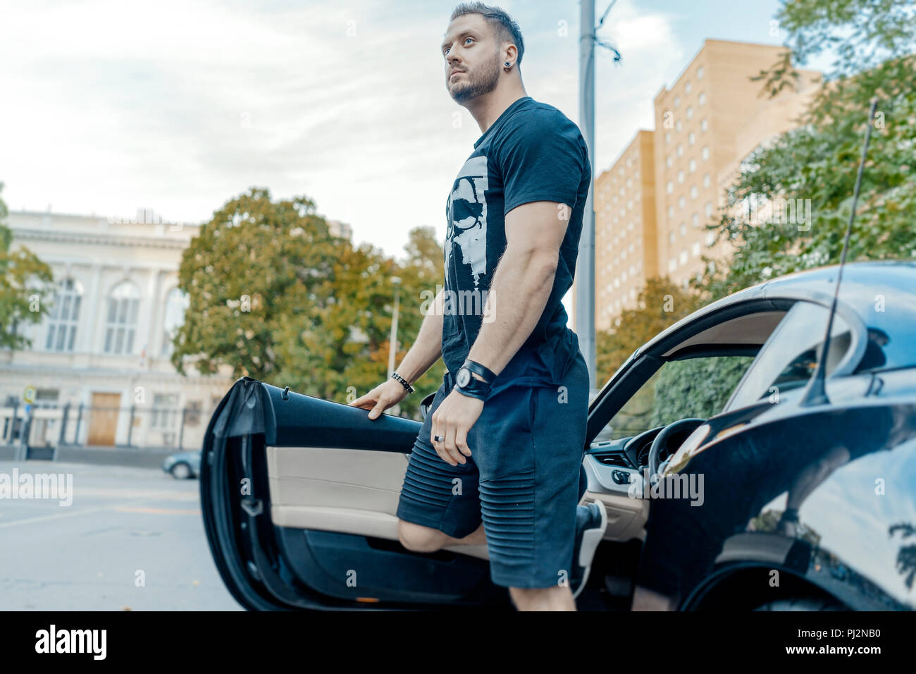 Close up of young attractive man getting out of the black car. Side ...