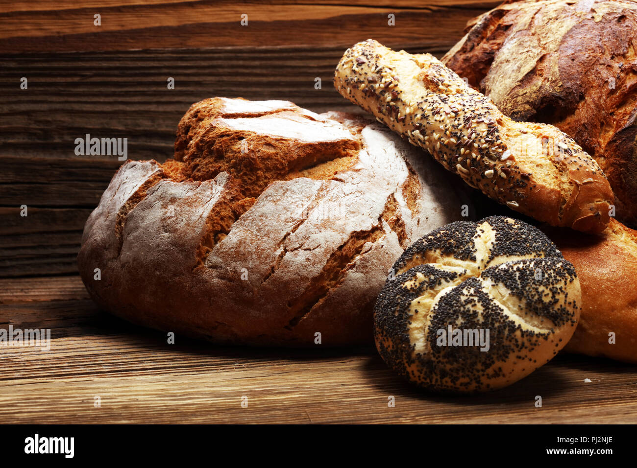 Different kinds of bread and bread rolls on board from above. Kitchen ...
