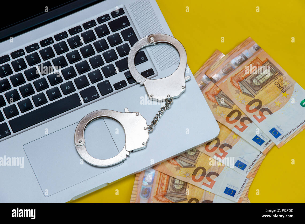 Handcuffs on keyboard, symbolizing cyber crime Stock Photo - Alamy