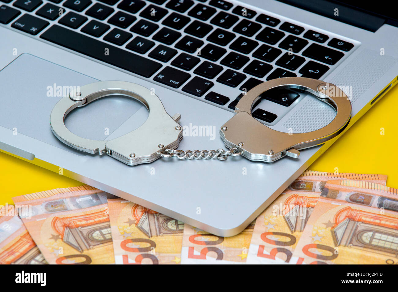 Handcuffs on keyboard, symbolizing cyber crime Stock Photo - Alamy
