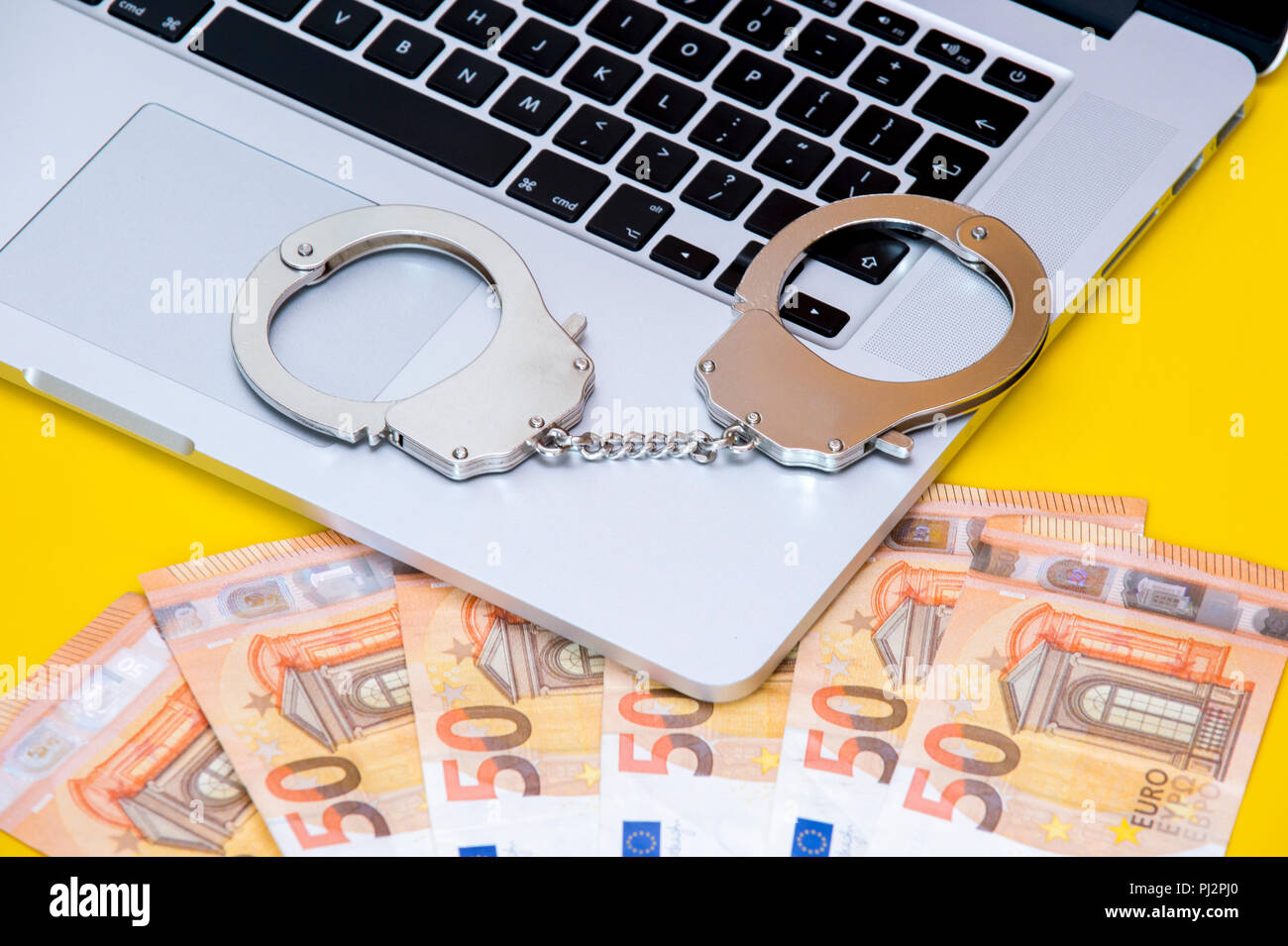Handcuffs on keyboard, symbolizing cyber crime Stock Photo - Alamy