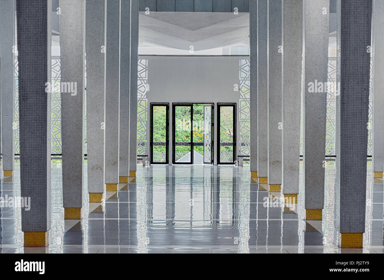 Long corridor between many columns, open doors in the end, symmetric ...