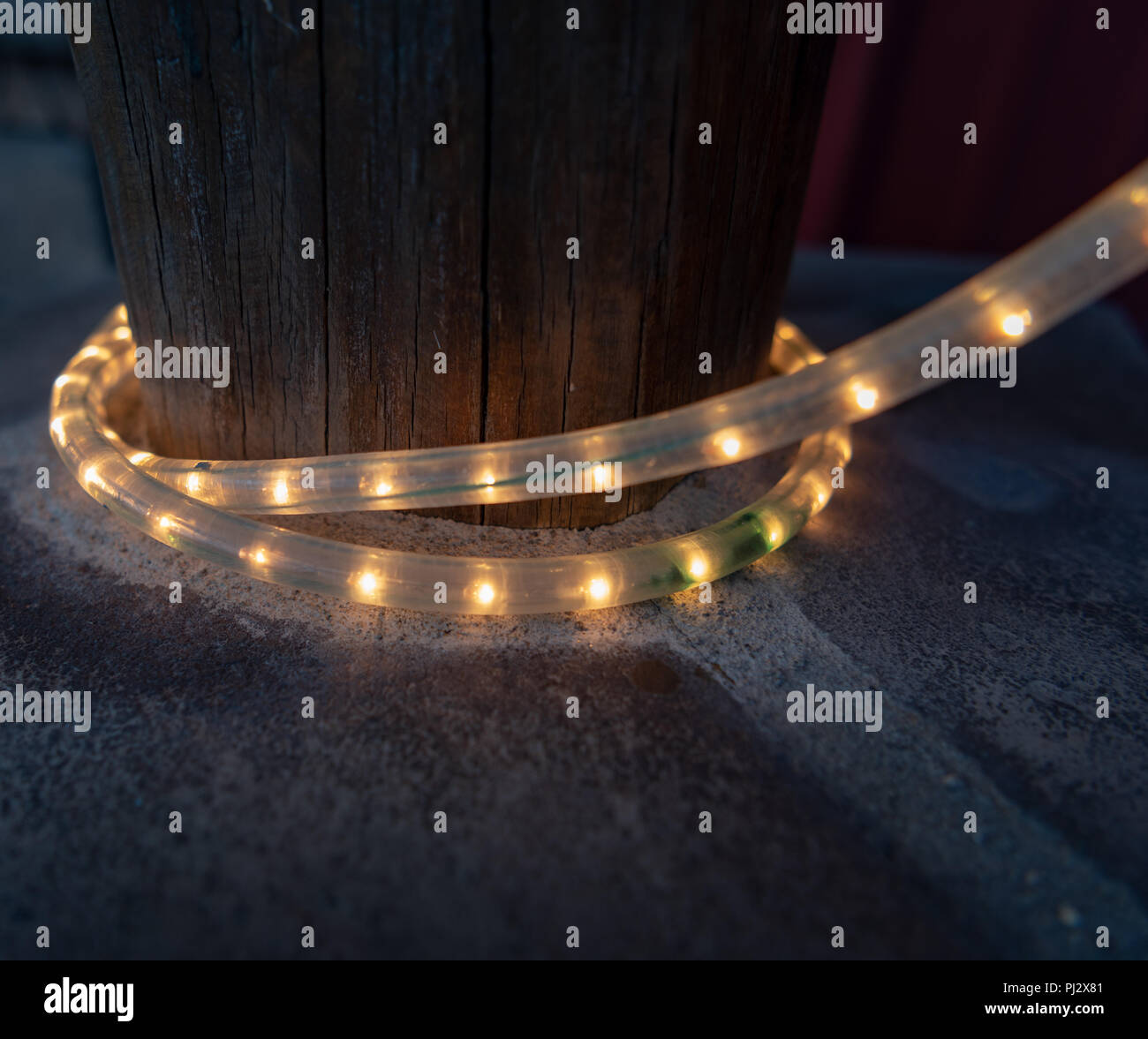 Tube of Lights Wrapped Around Wooden Post along sidewalk Stock Photo ...