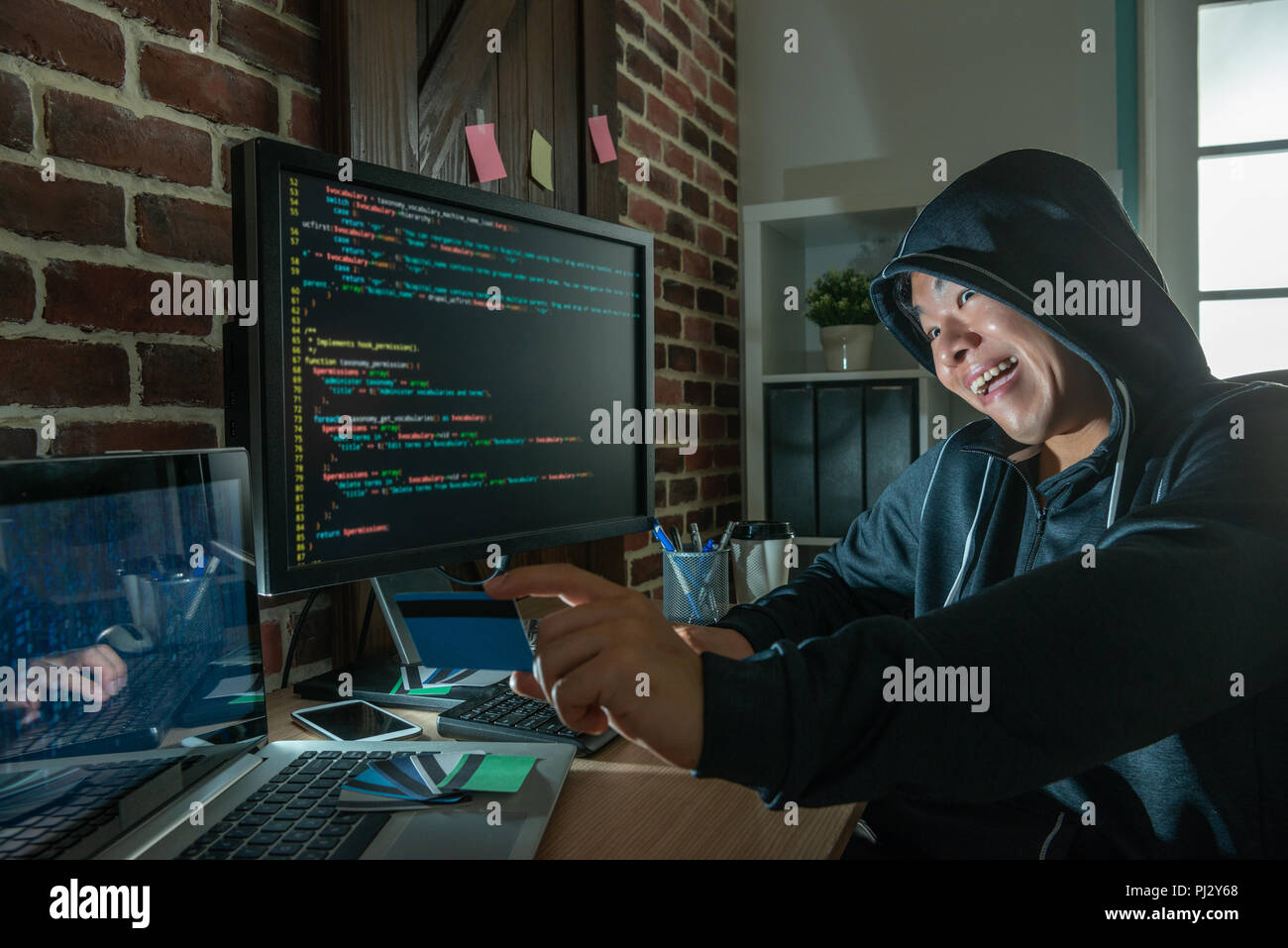 evil hacker holding one bank card and laughing vicously to ready for ...