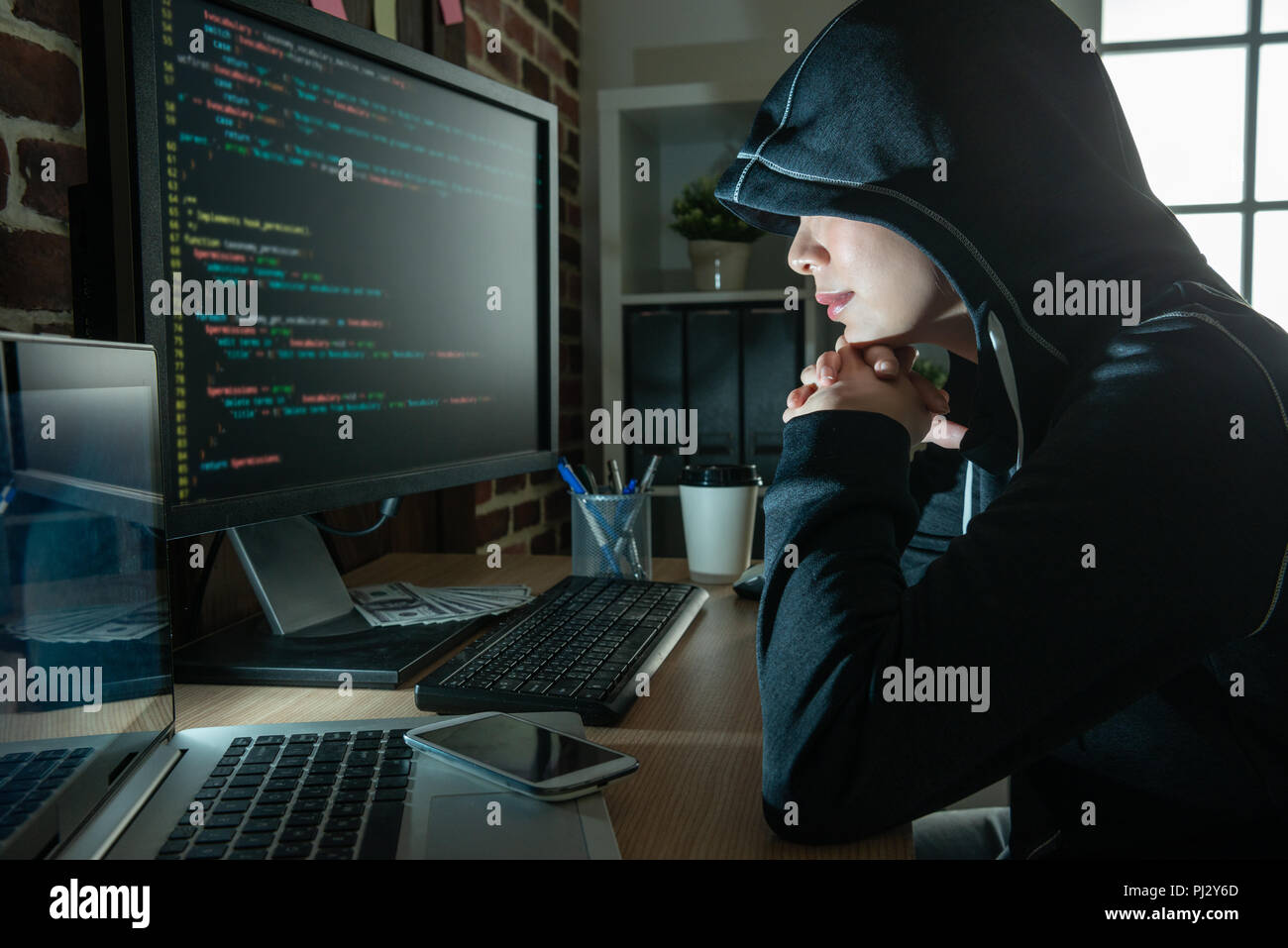 female hacker staring at the screen smiling. sitting in front of ...