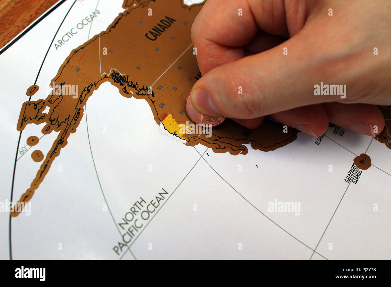 Man's hand scratching off visited places on a map. US travel. A travel ...