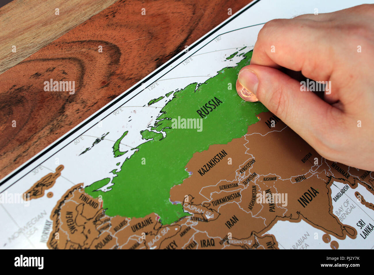 Man's hand scratching off visited places on a map. Russia travel. A ...