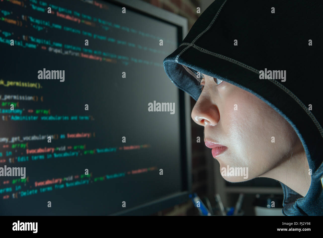 female hacker staring at the monitor seriously. closeup of side face ...