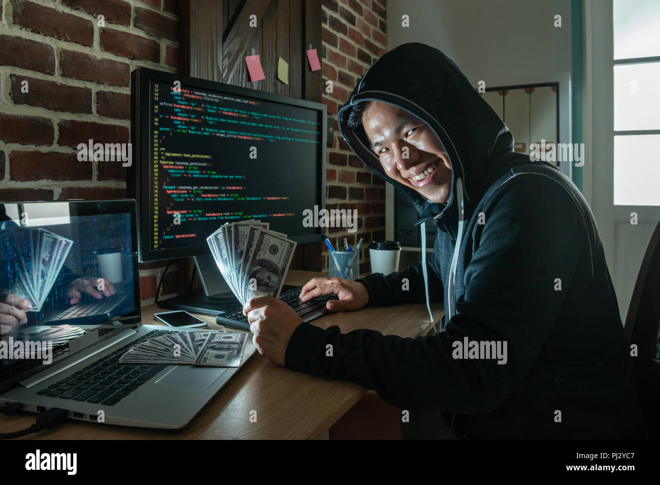 hacker looking round and holding banknote smiling with pure evilness at ...