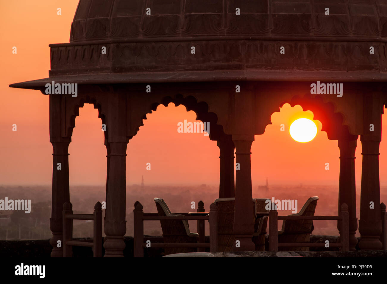 Sunset between the columns and the arches of a gazebo on the walls of ...