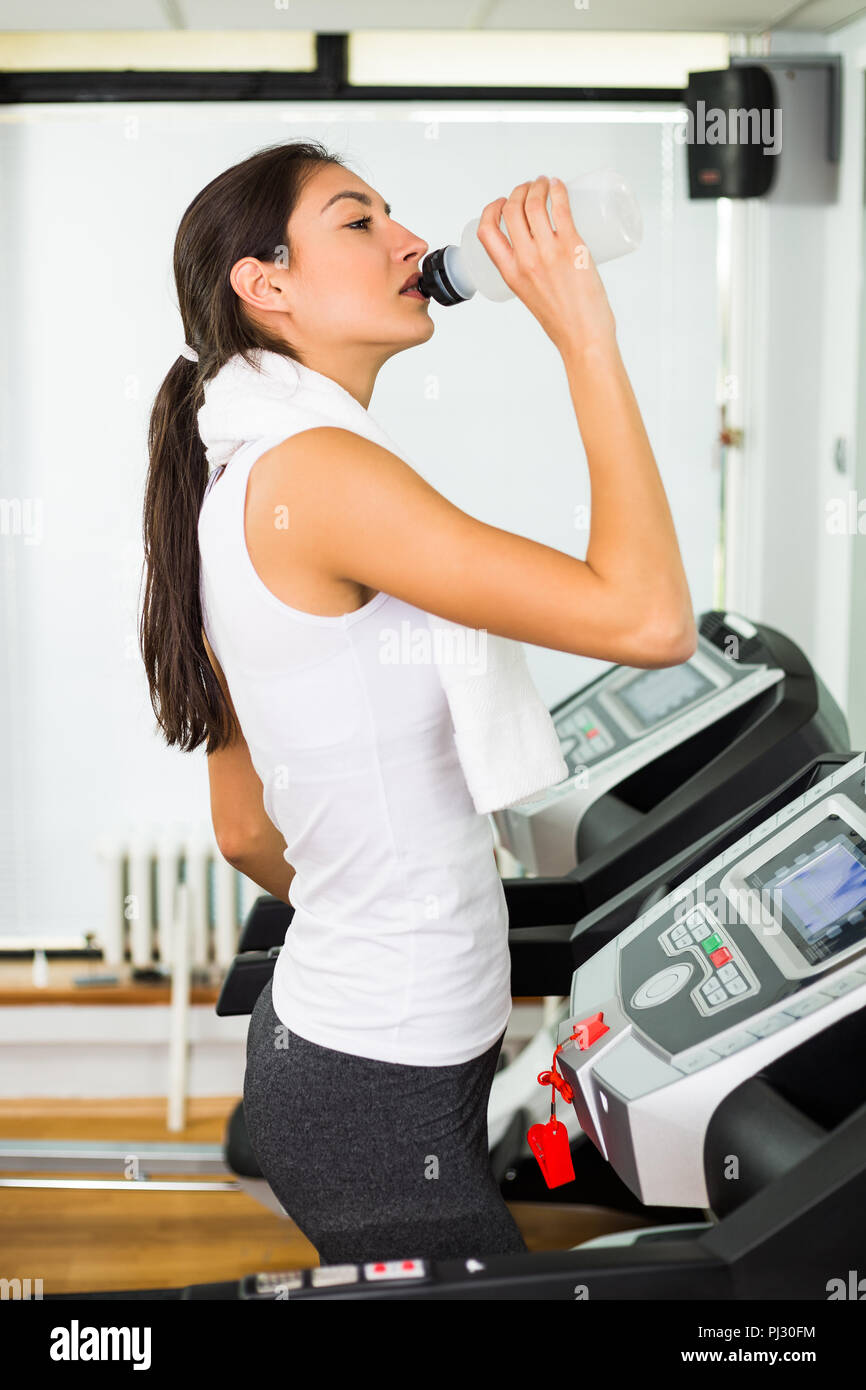 Fitness Woman Drinking Water While Exercising On Treadmill At The Gym