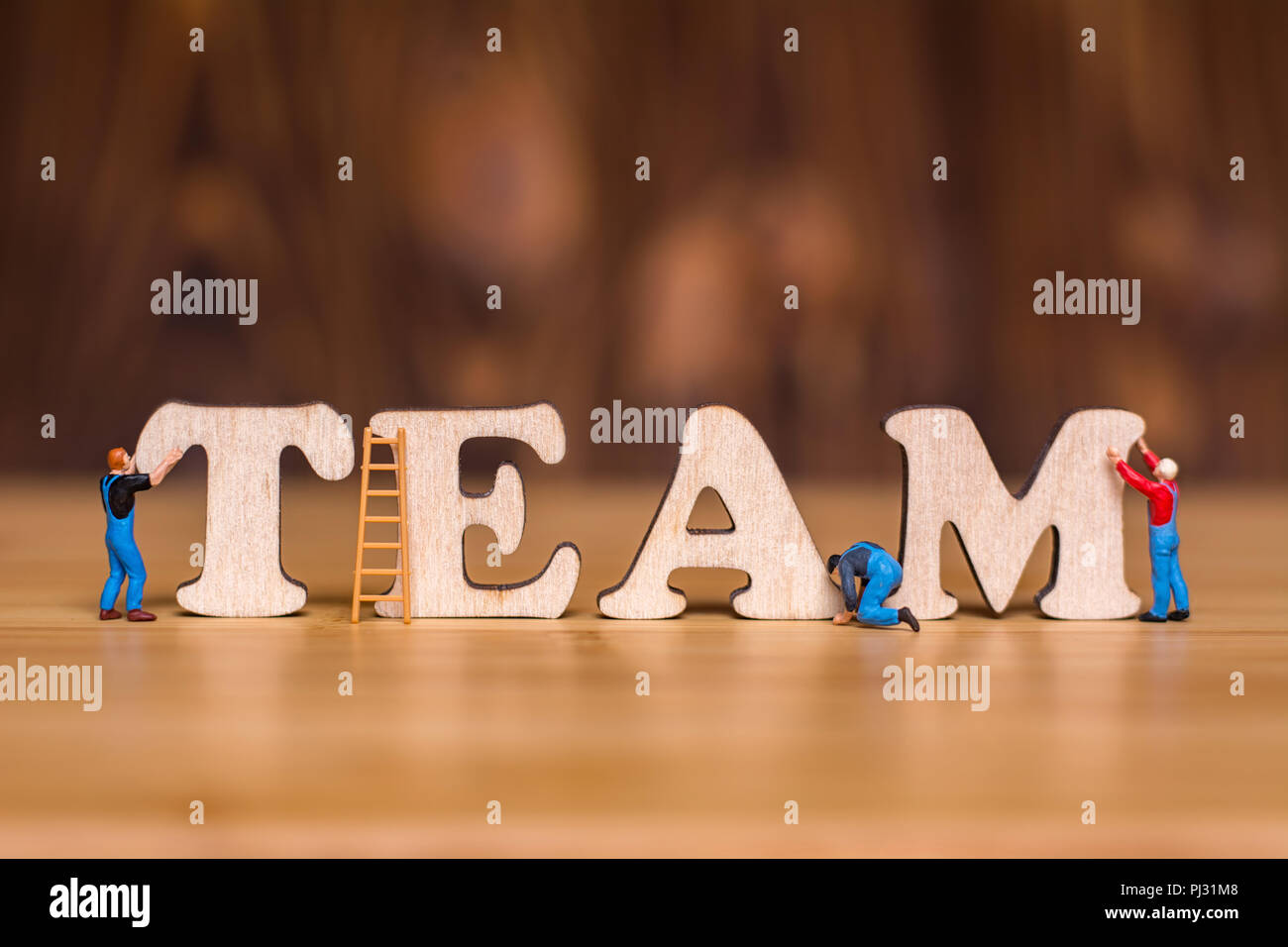 Creative concept about teamwork. Miniature people and wooden letters ...