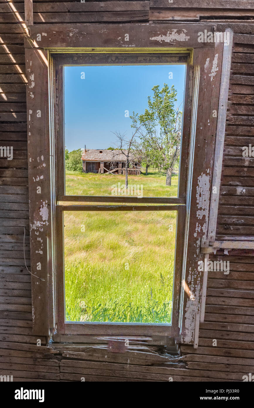 View through the window of an abandoned prairie farmhouse looking out ...