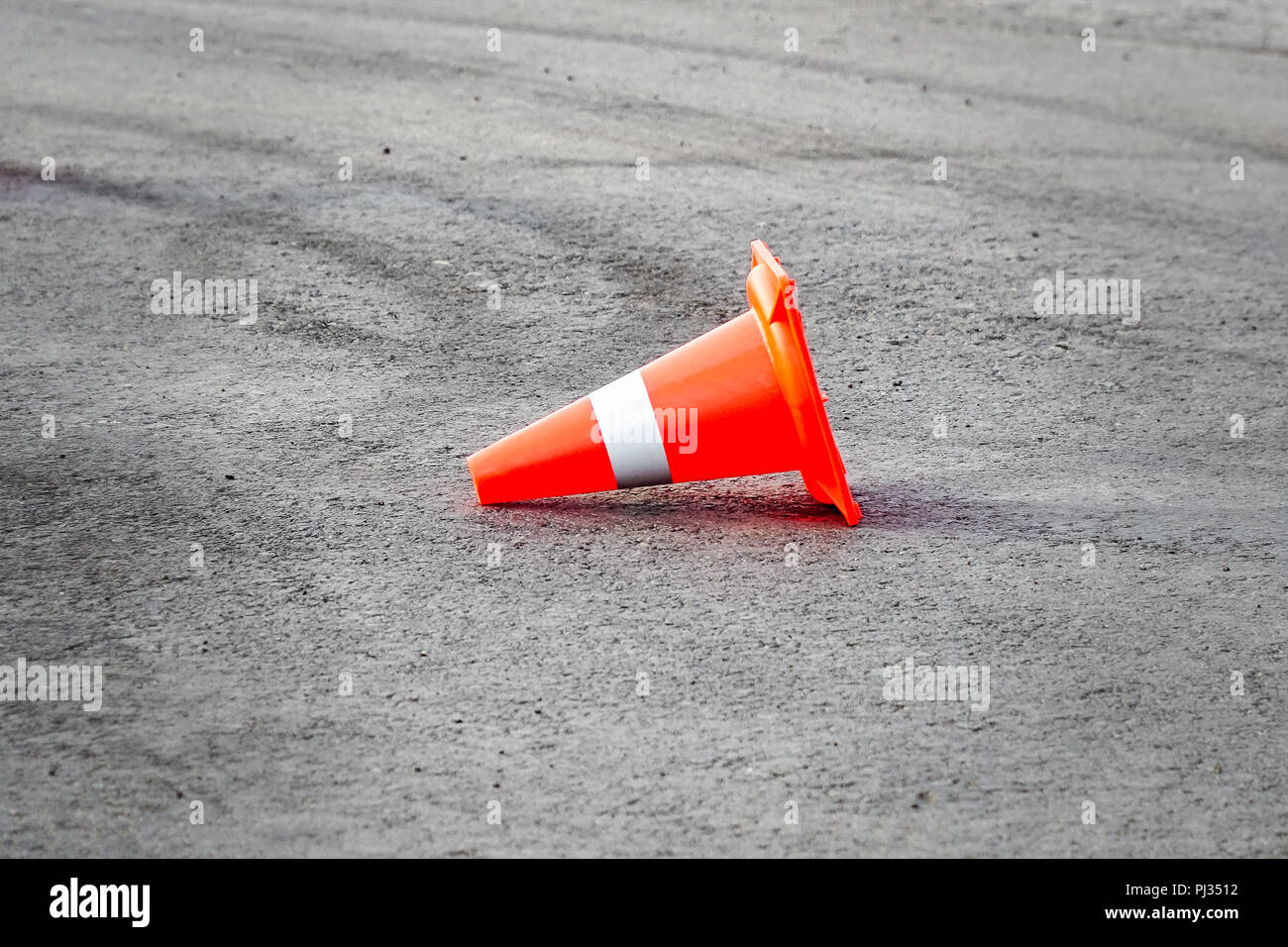 Traffic cone tipped over on pavement Stock Photo - Alamy