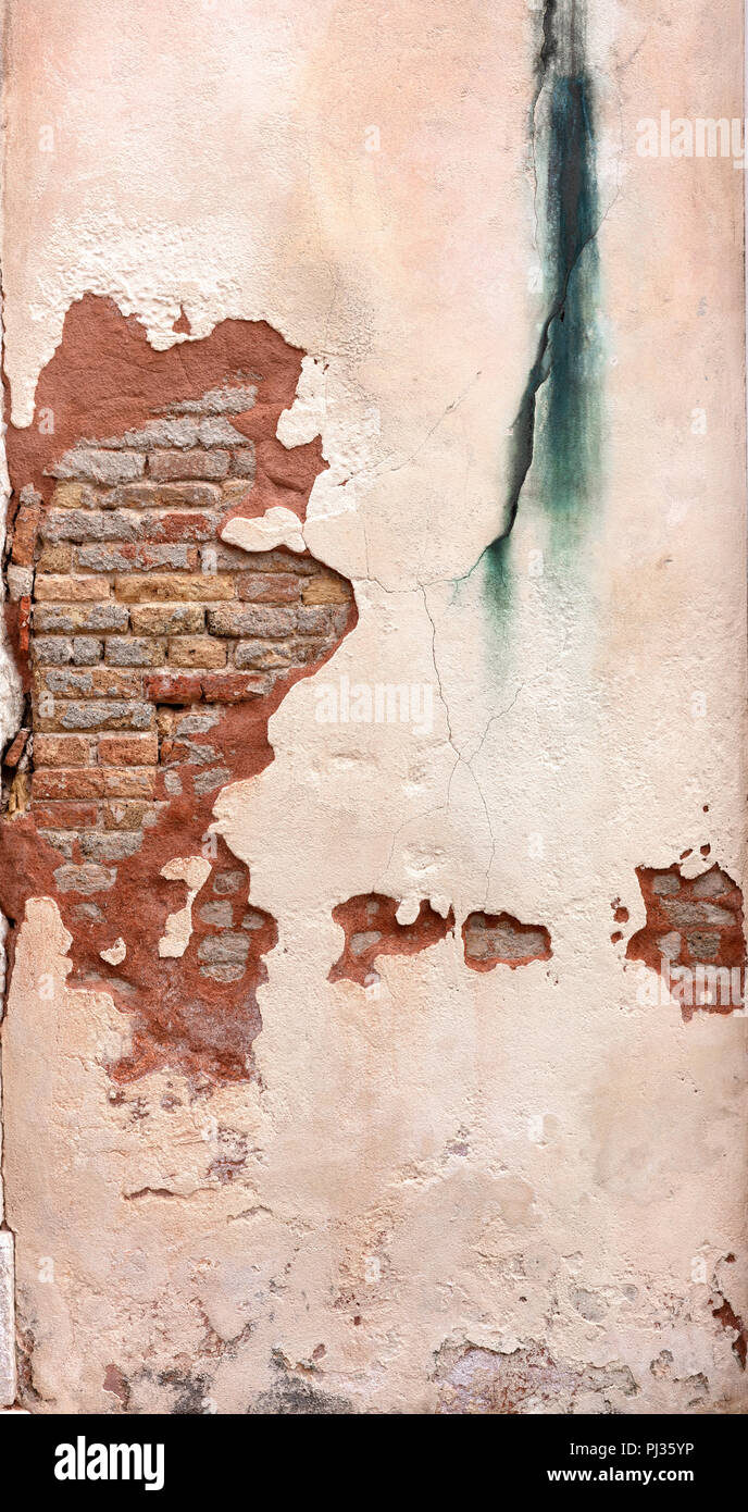white wall of lime with damage showing the interior of reddish bricks ...
