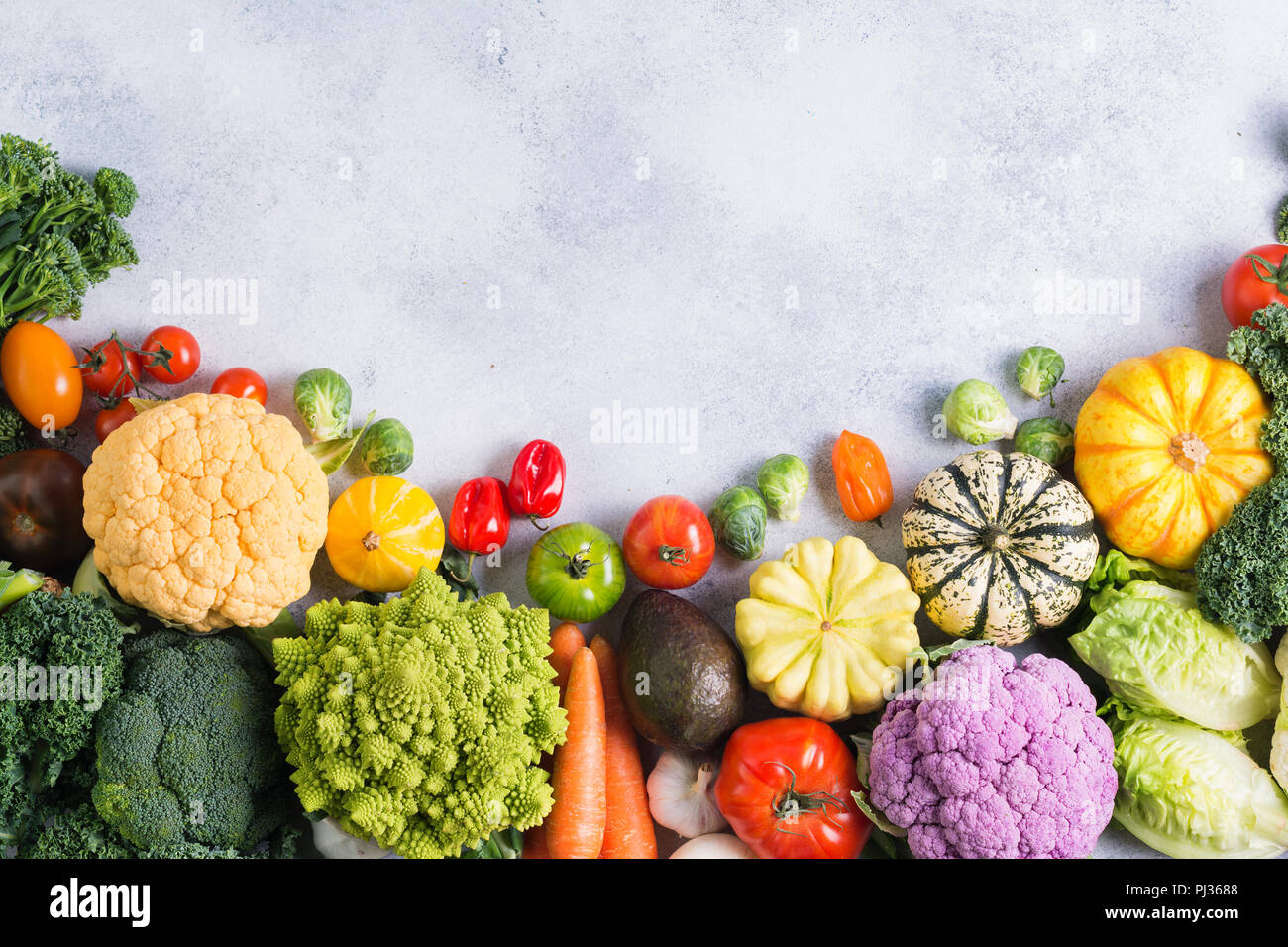 Above view of different colored rainbow vegetables on the light grey ...