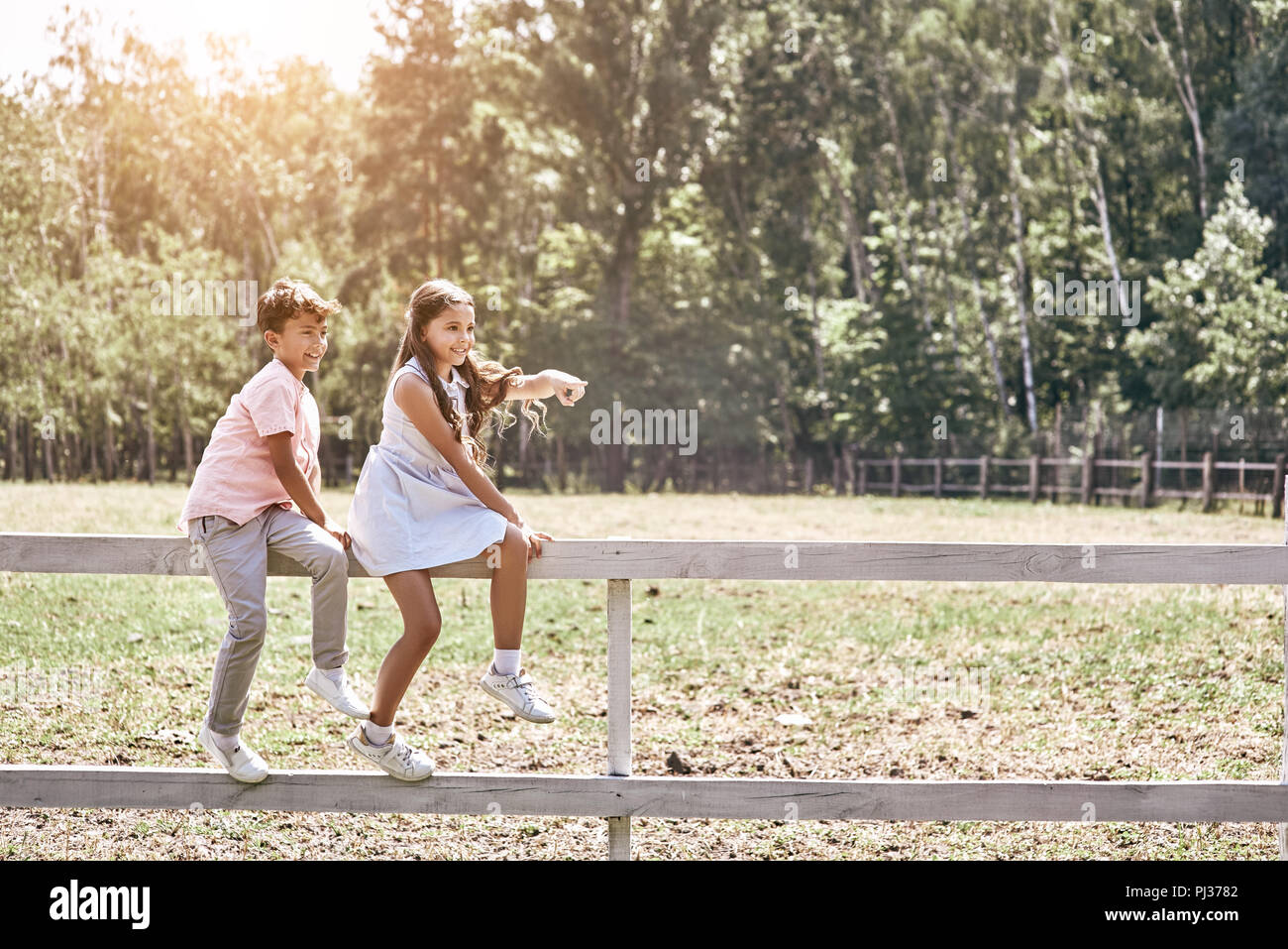 Friendship. Little boy looking at girl pointing aside sitting on Stock Photo - Alamy