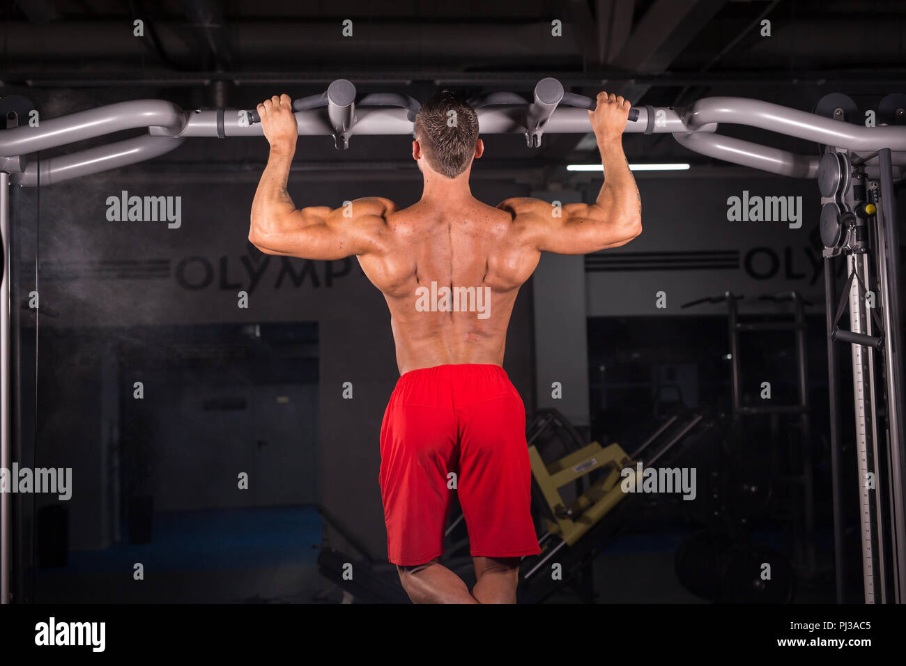 Strong young man doing pull up exercise on horizontal bar in gym Stock ...