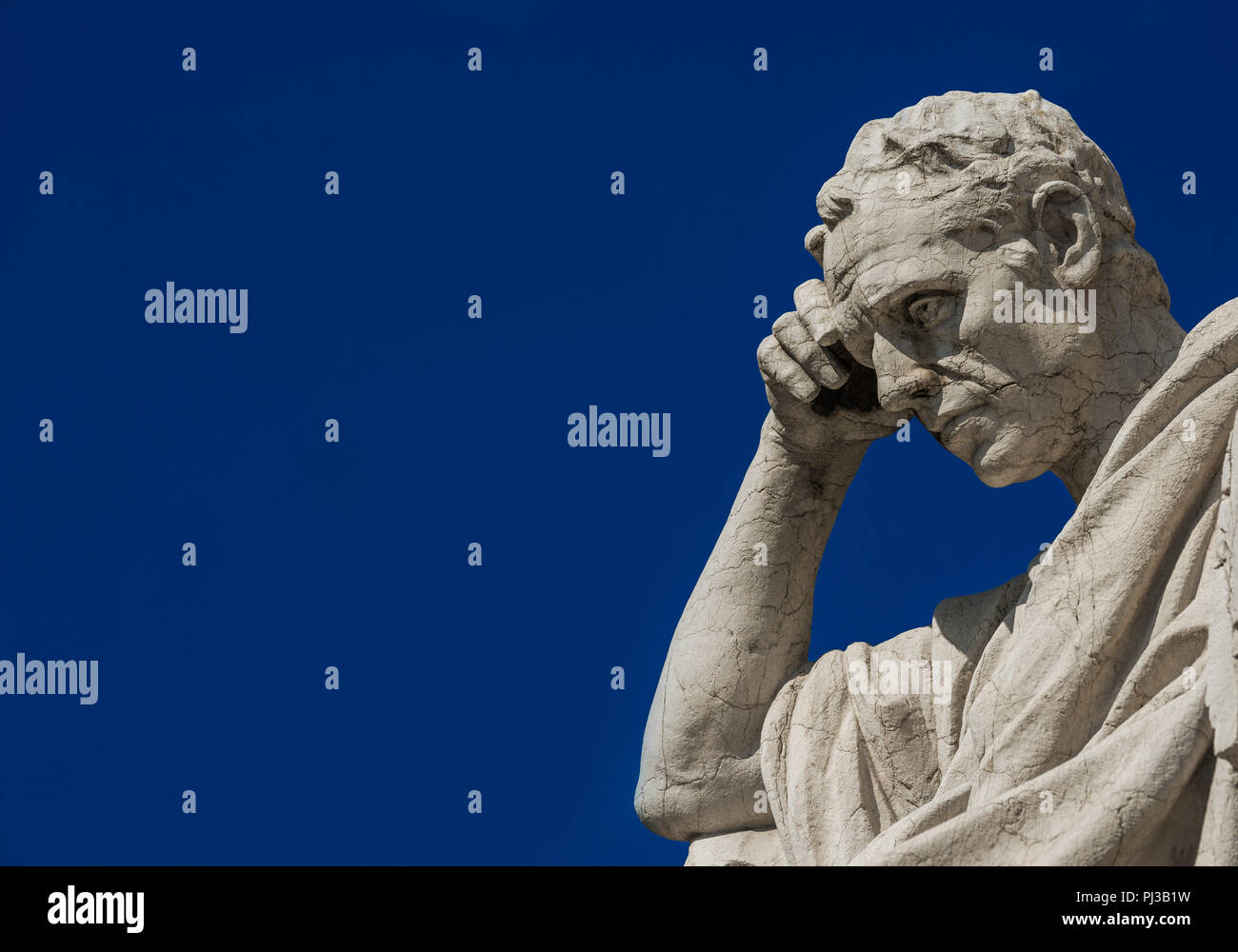 Man statue in the act of thinking against blue sky. Ancient Roman ...