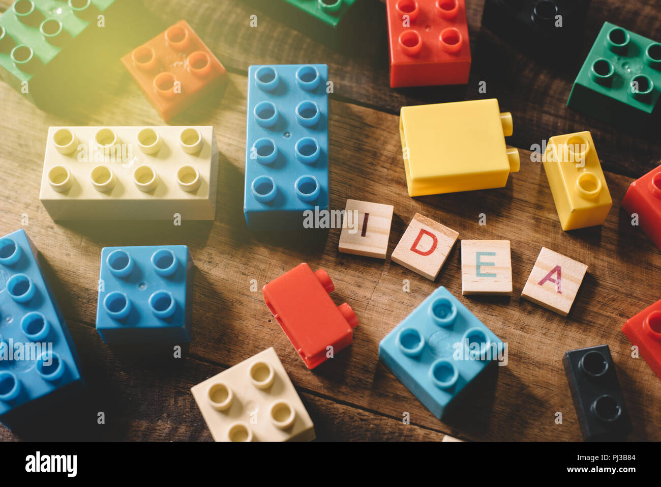 Toy plastic bricks on wooden table with alphabet tiles word IDEA ...