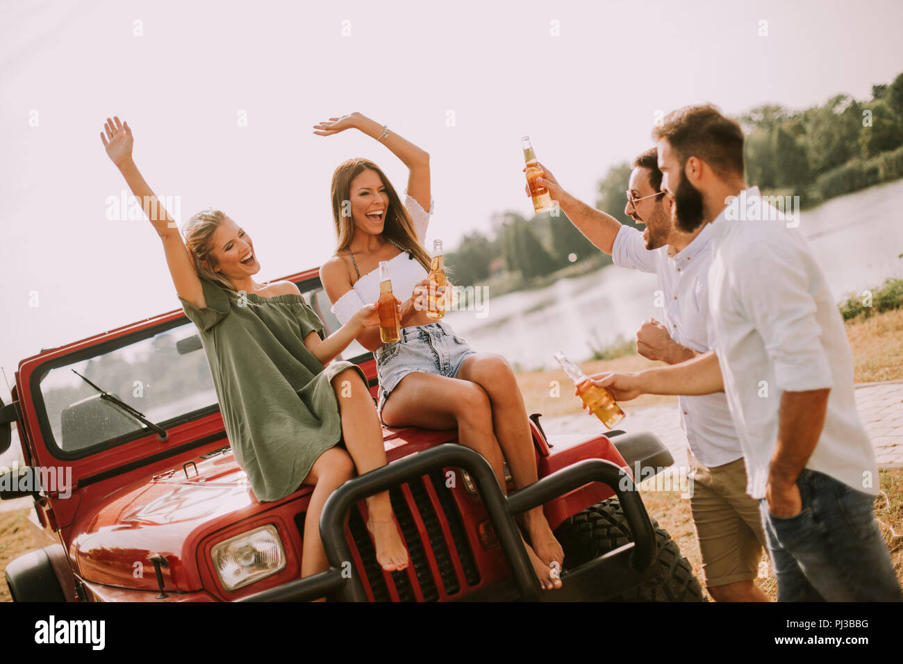 Young people drinking and having fun by car outdoor at hot summer day ...