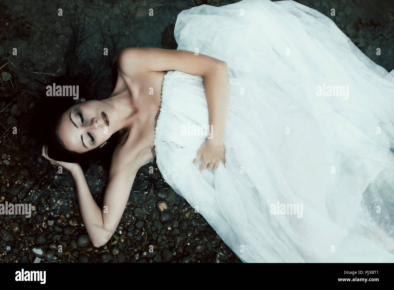 Woman lying on the shore in white dress, dark mystery scene Stock Photo ...