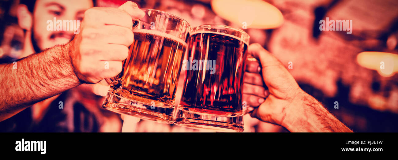Two young men toasting their beer mugs Stock Photo - Alamy