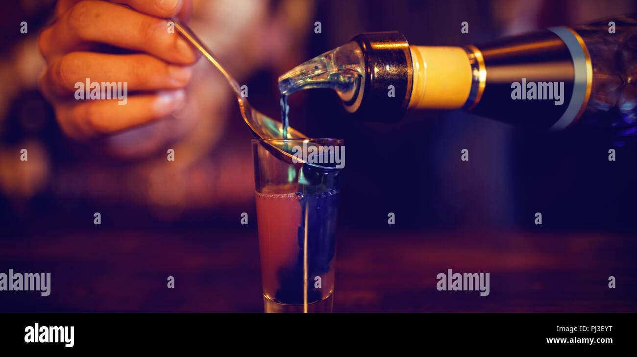 Waiter pouring cocktail drink into shot glasses at counter Stock Photo ...